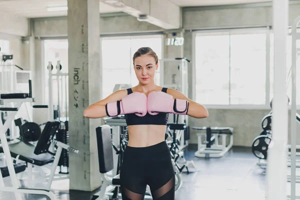 Beautiful girls exercise by boxing in the gym. She wears a pink boxing ...