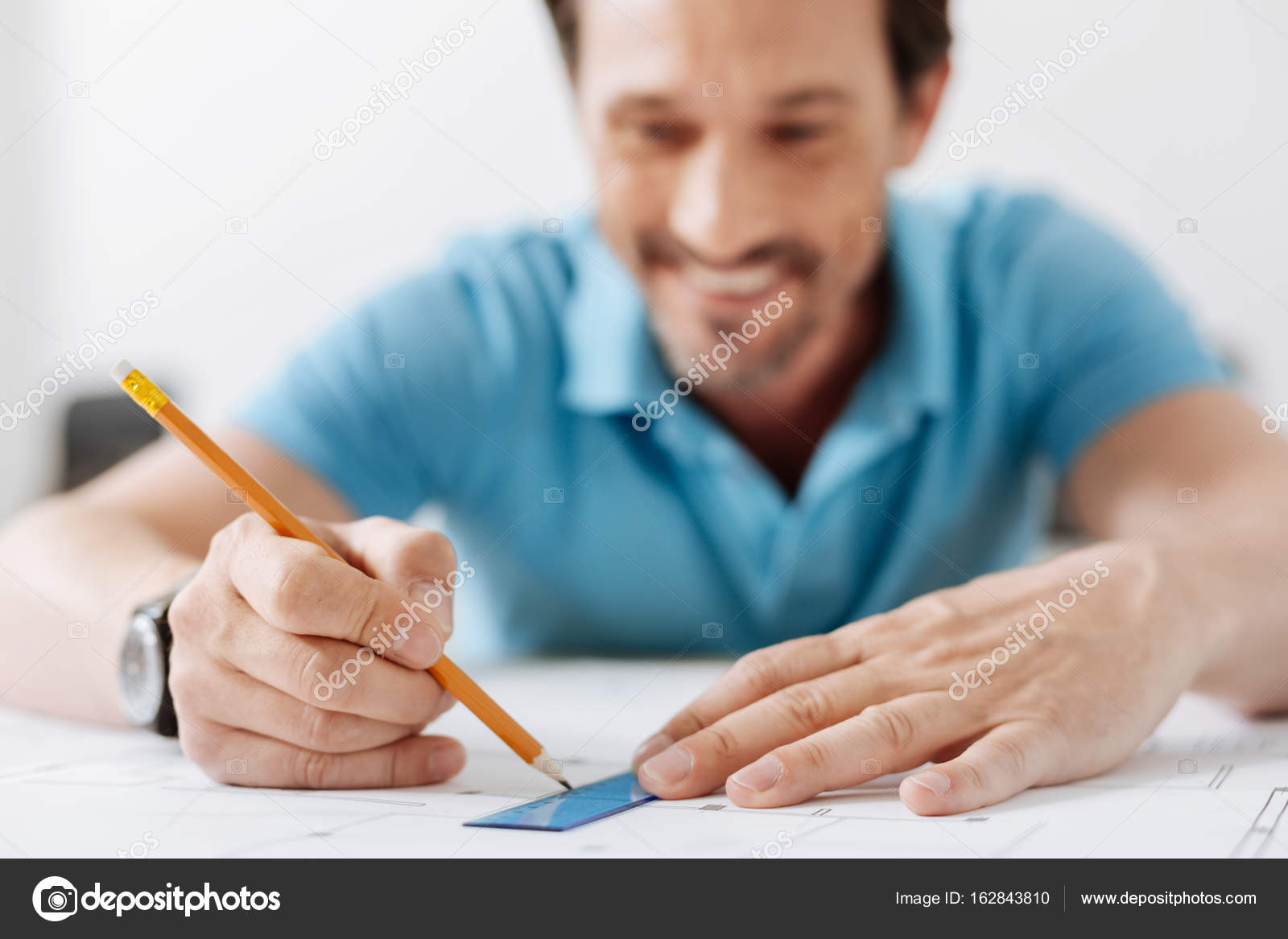 Smiling young man drawing a line on a blueprint Stock Photo by ...