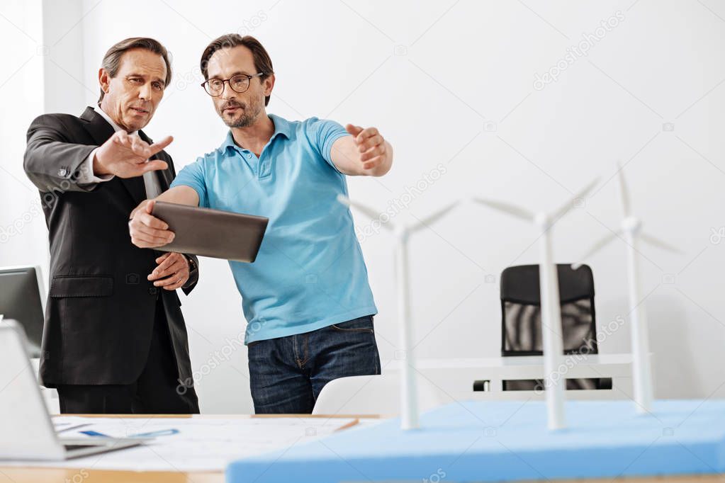 Dos ingenieros discutiendo el tamaño de un modelo de central eólica 2024