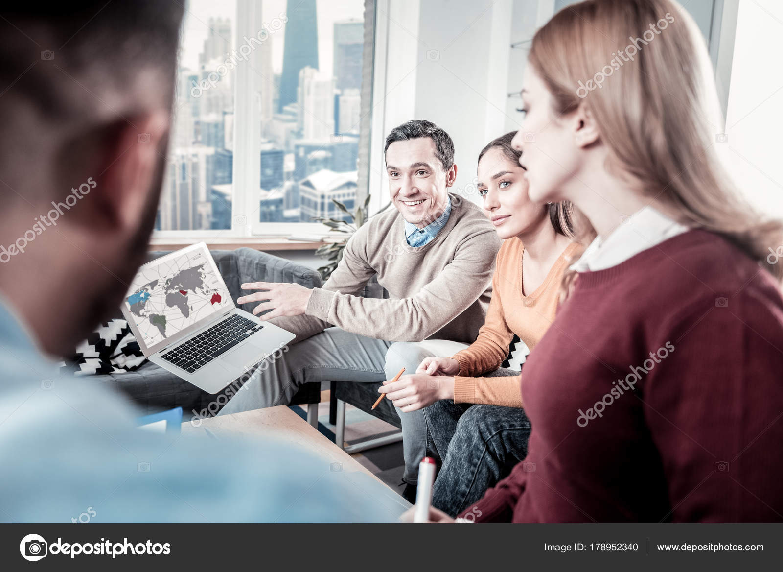 Smart nice-looking workers sitting and looking at the laptops screen ...