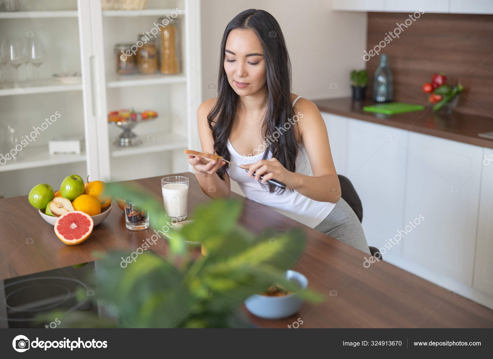 Female smearing her bread with almond butter Stock Photo by ©yacobchuk1 324913670