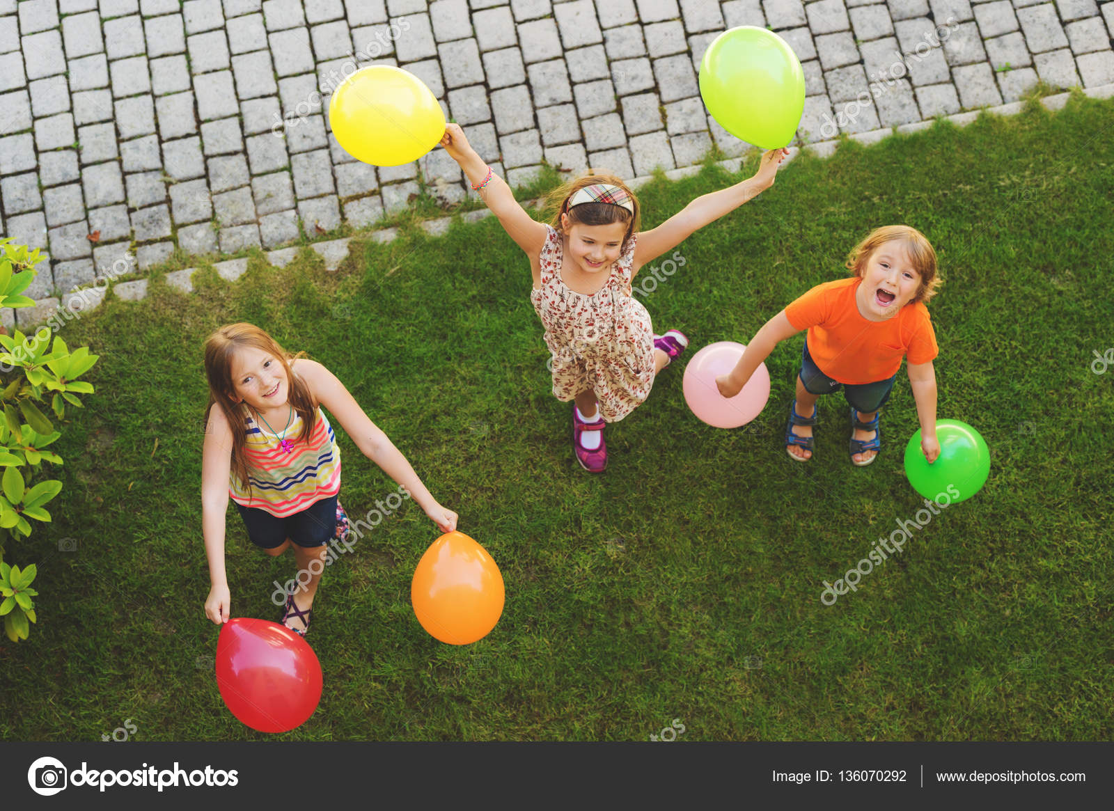 Three happy little kids playing with colorful balloons outdoors, top ...
