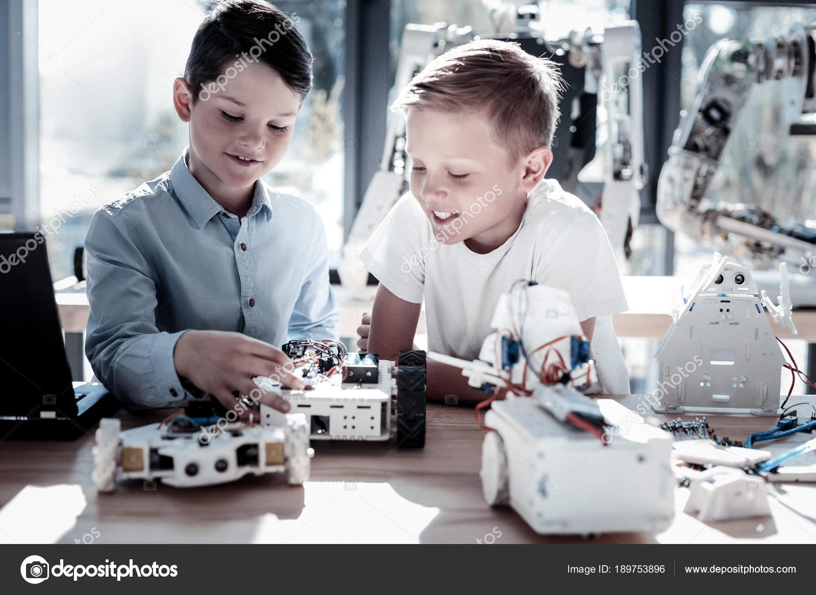 Relaxed kids constructing robotic machines with smiles on their faces ...
