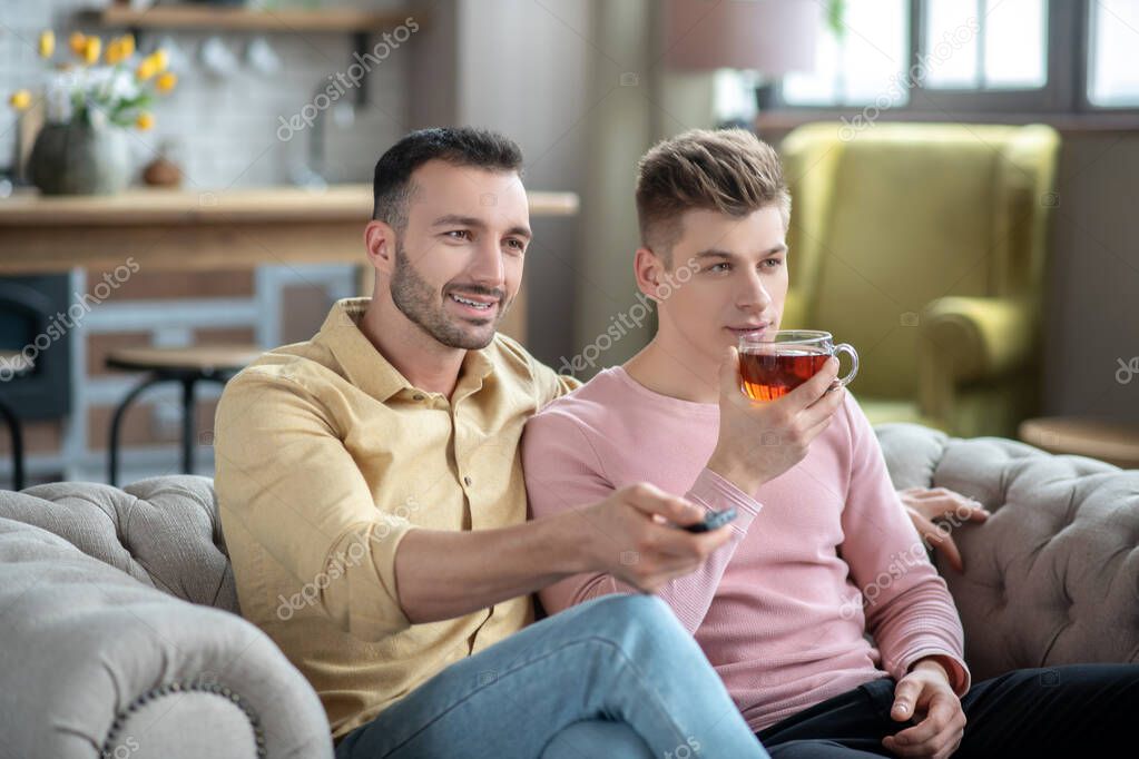 Dos j venes tomando t y viendo televisi n juntos en casa 2024