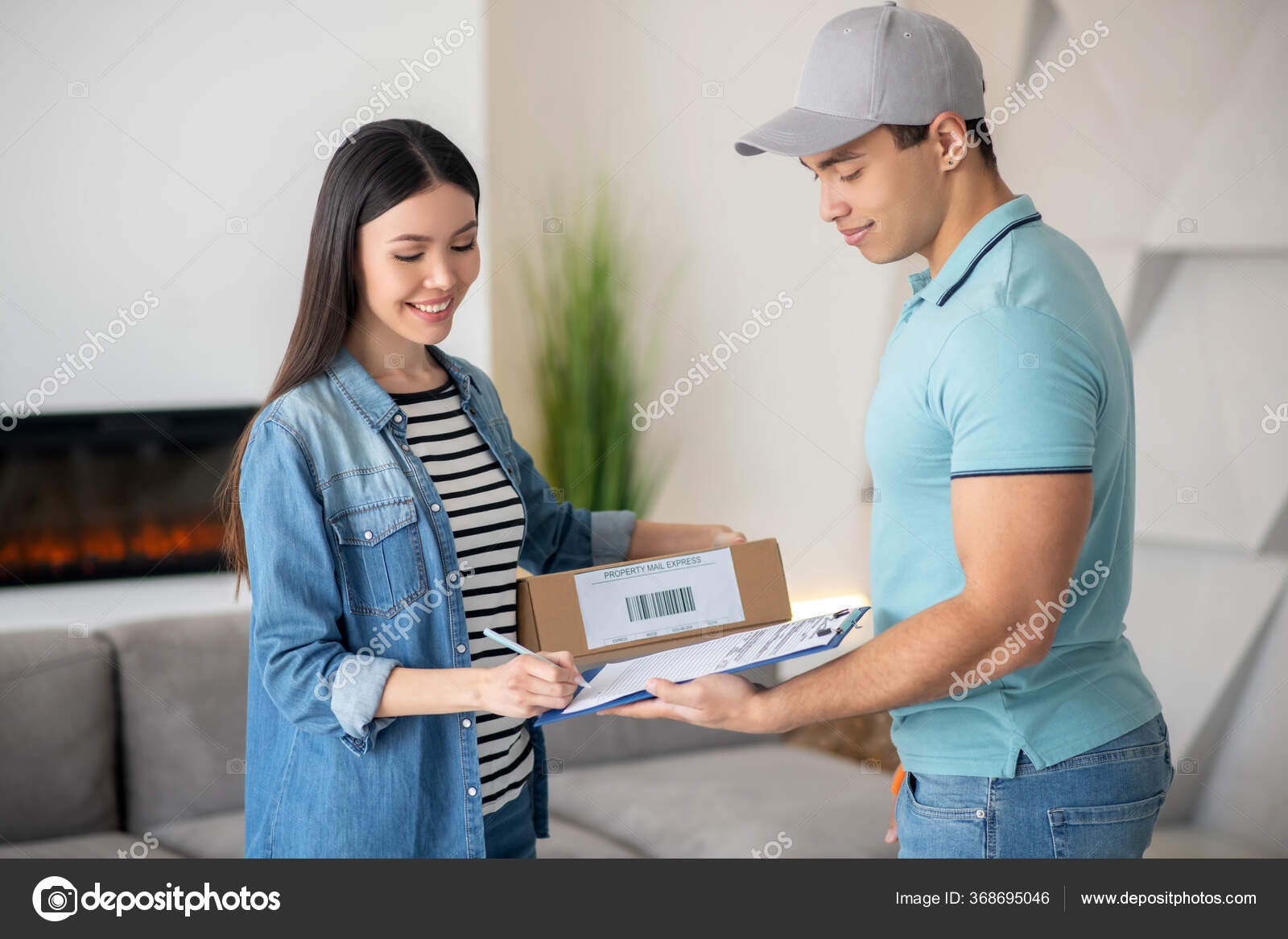 Dark-haired female holding parcel and signing delivery documents ...