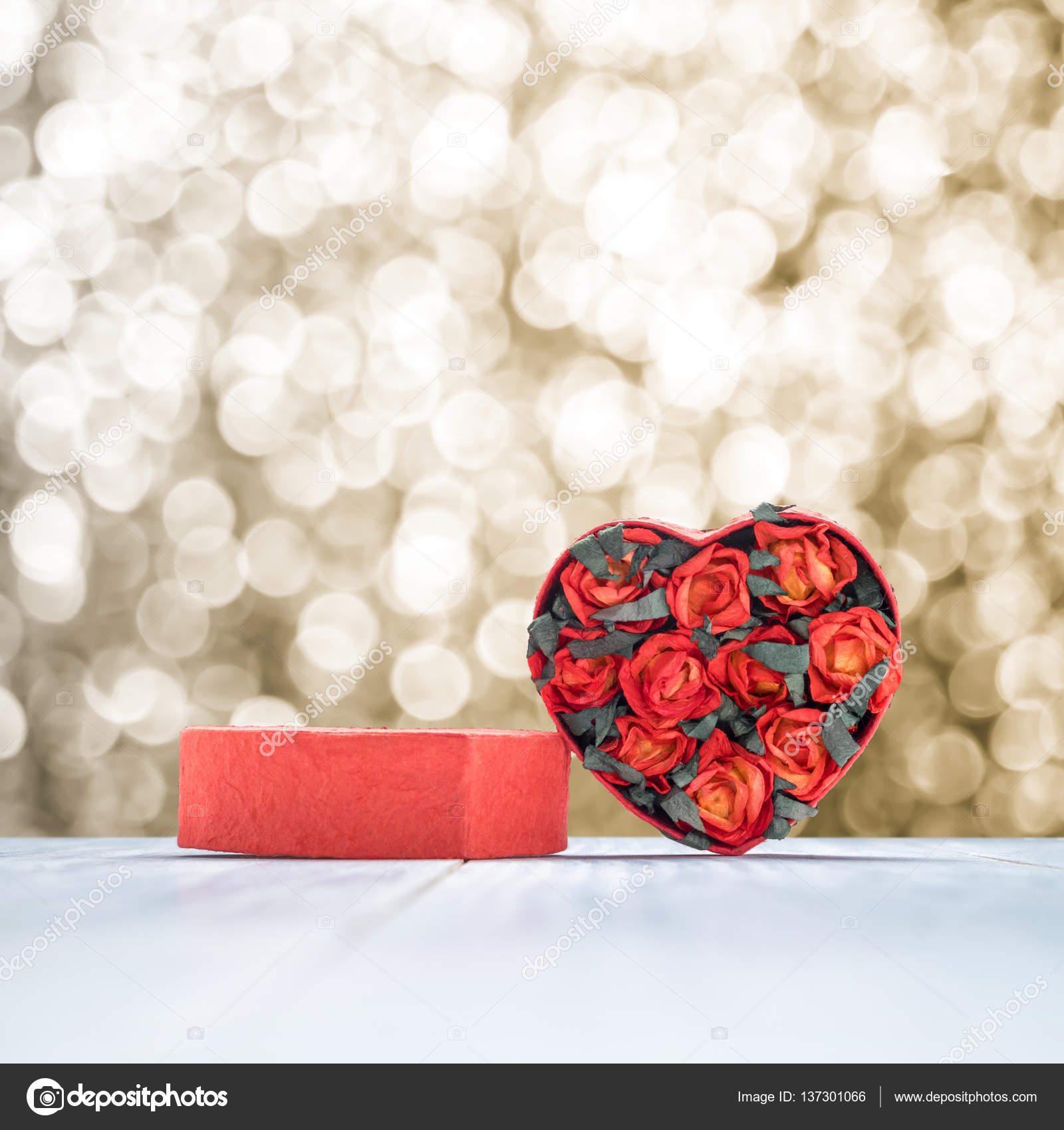 Heart shape box with red roses inside on white wood table top at ...