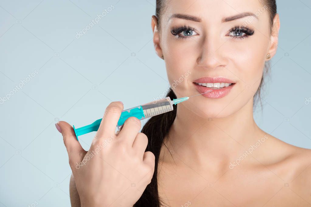 Mujer joven sonriente que se inyecta los labios 2023