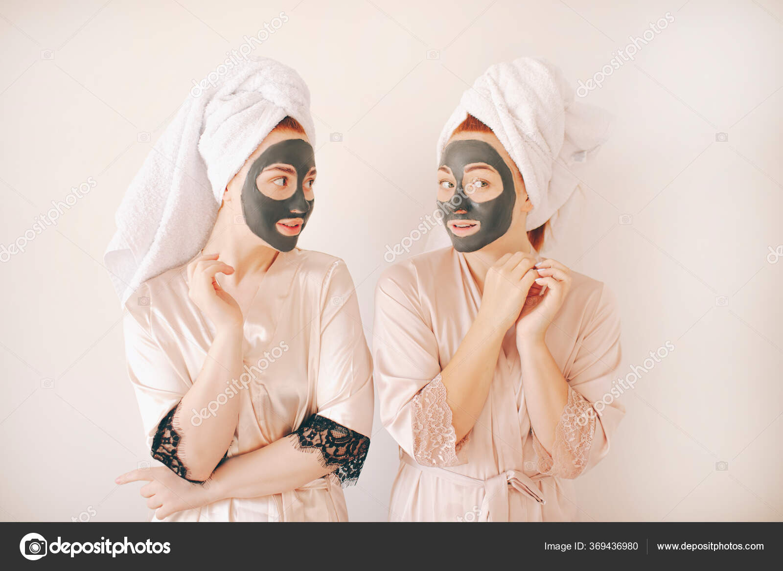 Two young women sisters in bathrobes with towels on their heads ...