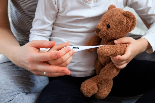 madre e hijo miden la temperatura del oso de peluche. Concepto de ...