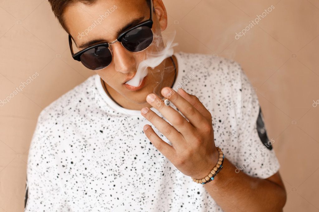 Young handsome guy smoking a cigarette. Clouds of smoke. Stock Photo by ...