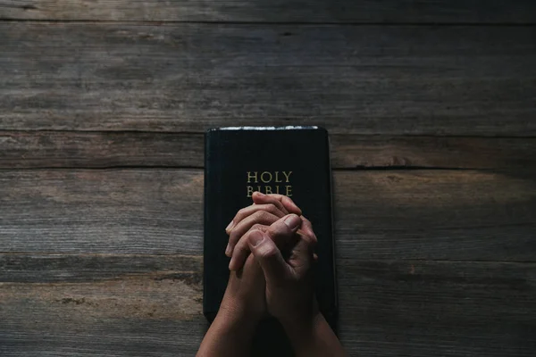 Hands folded in prayer on a Holy Bible in church concept for faith - Stock Image - Everypixel