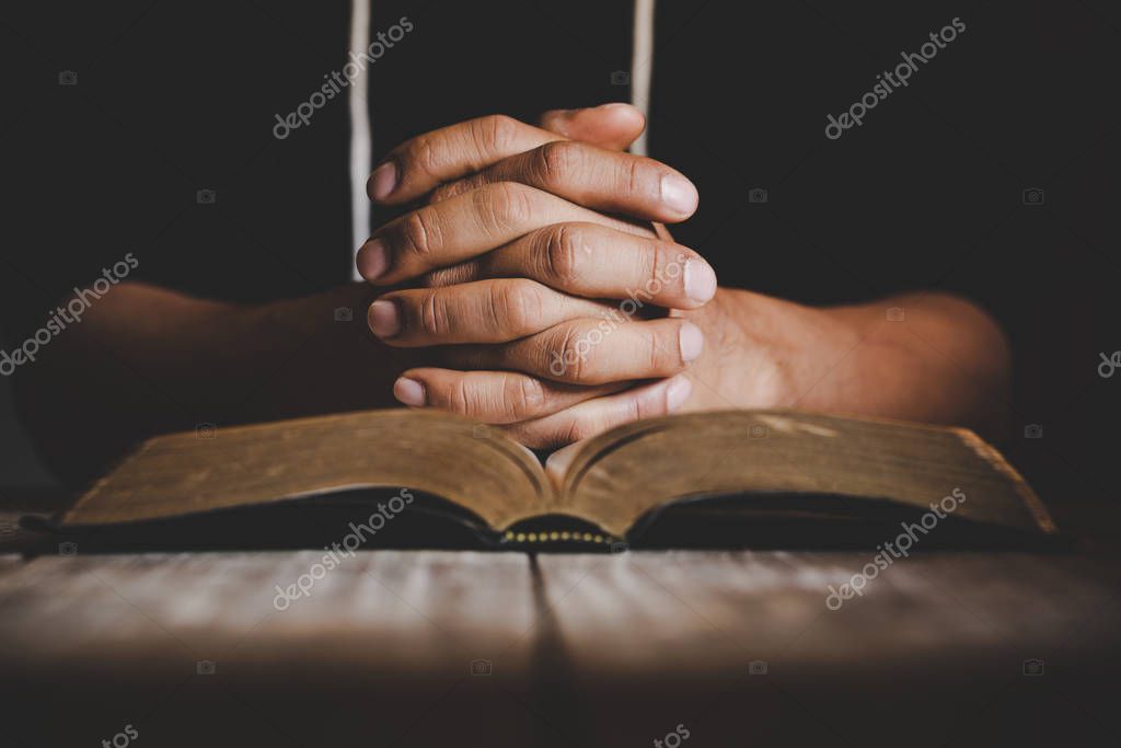 Enfoque suave en una mano del hombre mientras reza por la religión ...