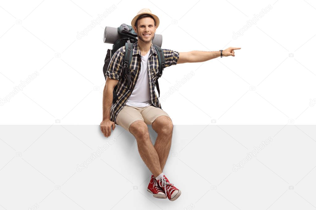 Turista sentado en un panel y señalando aislado sobre fondo blanco 2024