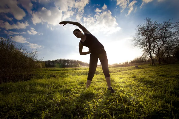 woman stretching out on the field / doing yoga / before jogging - Stock ...