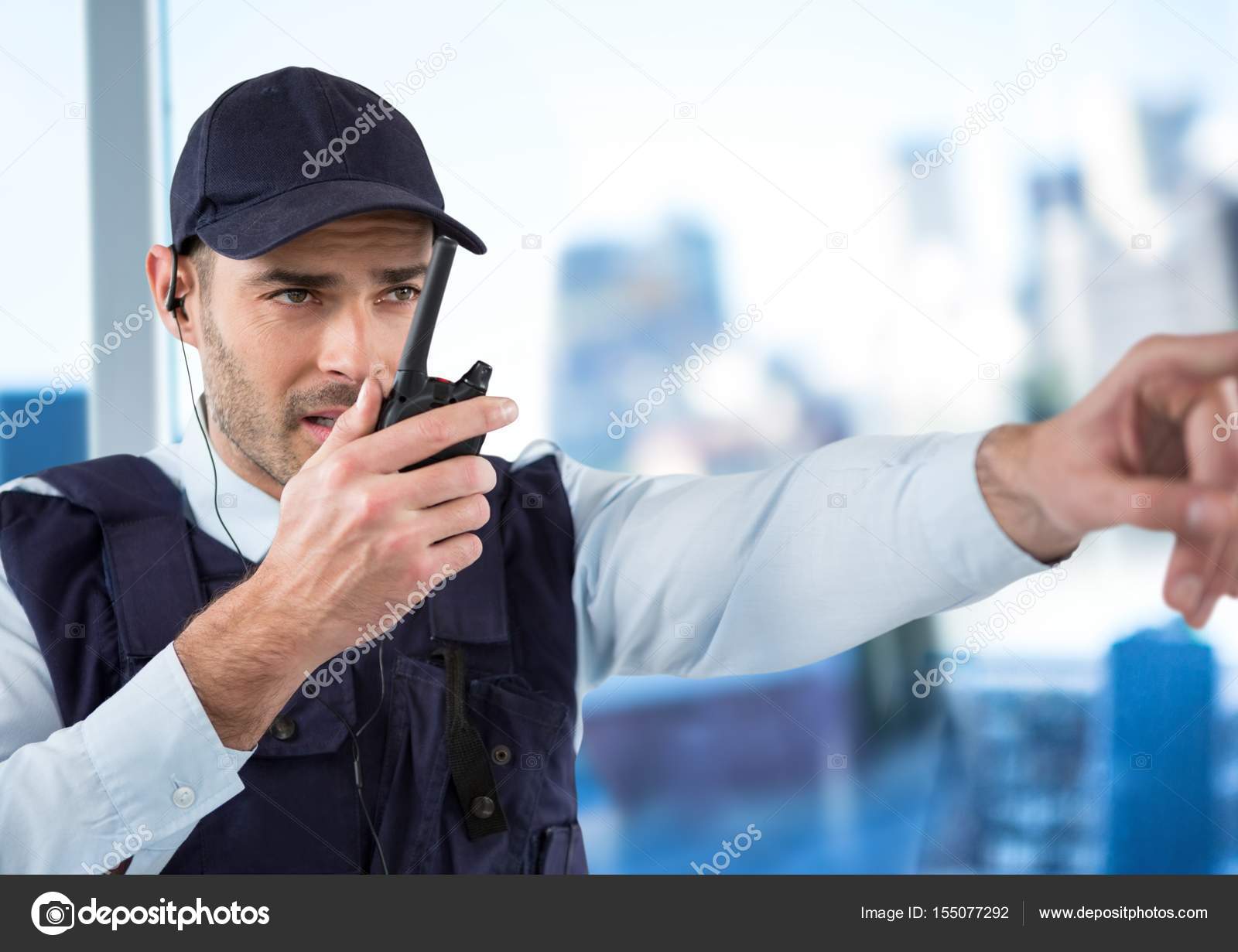 Security guard with walkie talkie pointing against blurry window ...