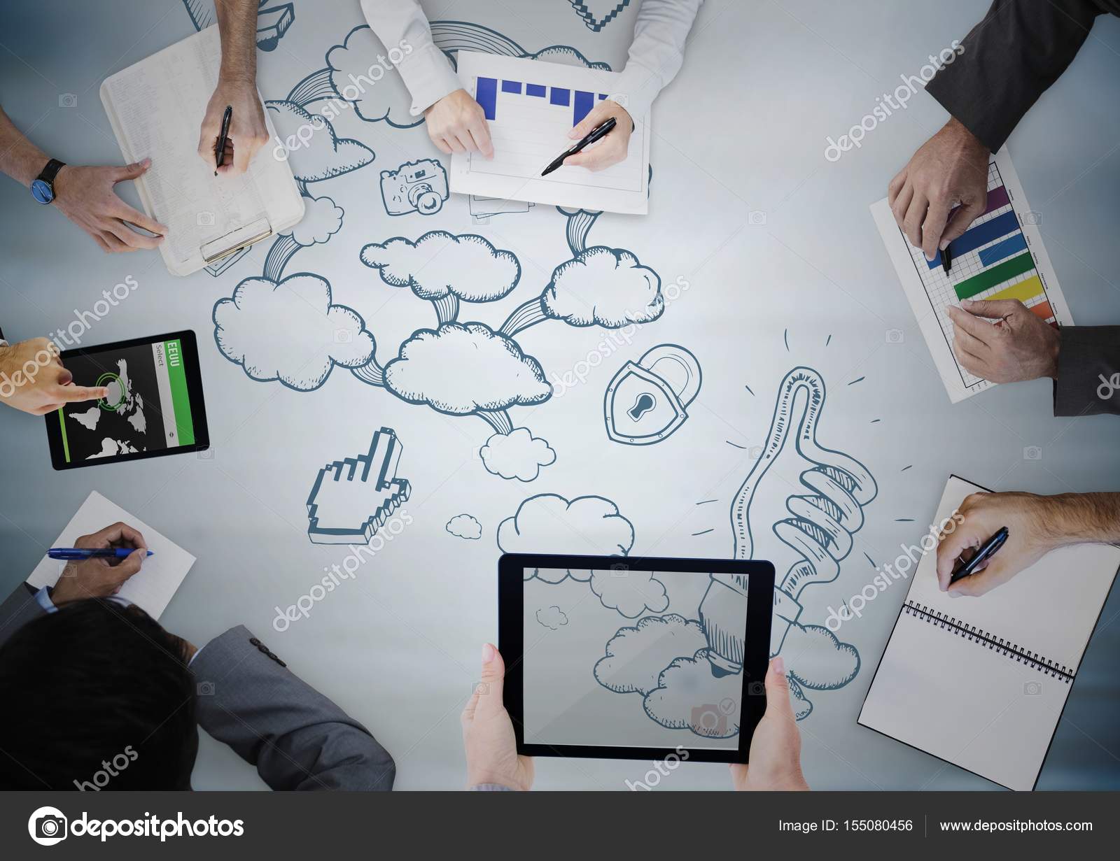 Overhead of hands writing with blue surface and and blue cloud doodles ...