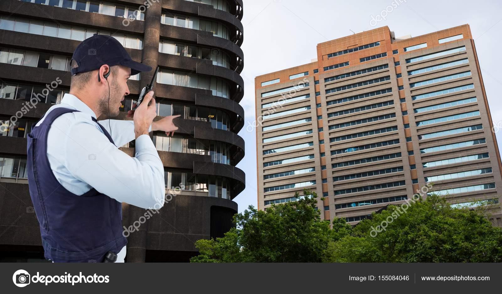 Security guard pointing at buildings while talking on walkie talkie ...