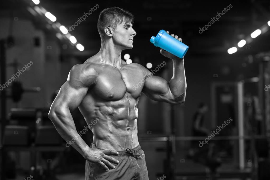 Hombre musculoso bebiendo agua en el gimnasio, en forma abdominal ...