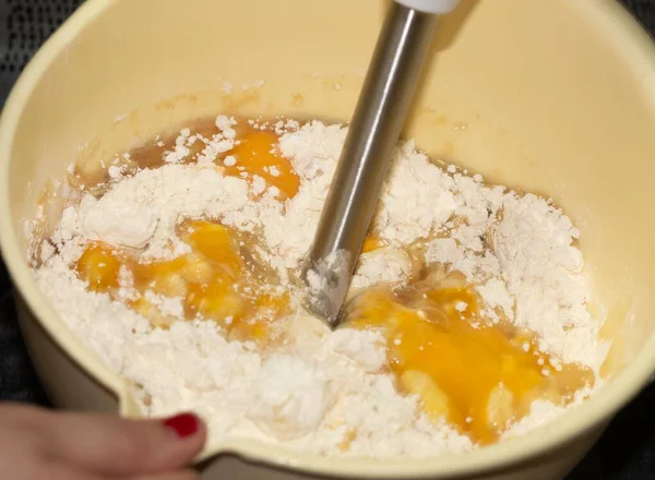 beating with the mixer the dough of the cake with flour and eggs in the ...