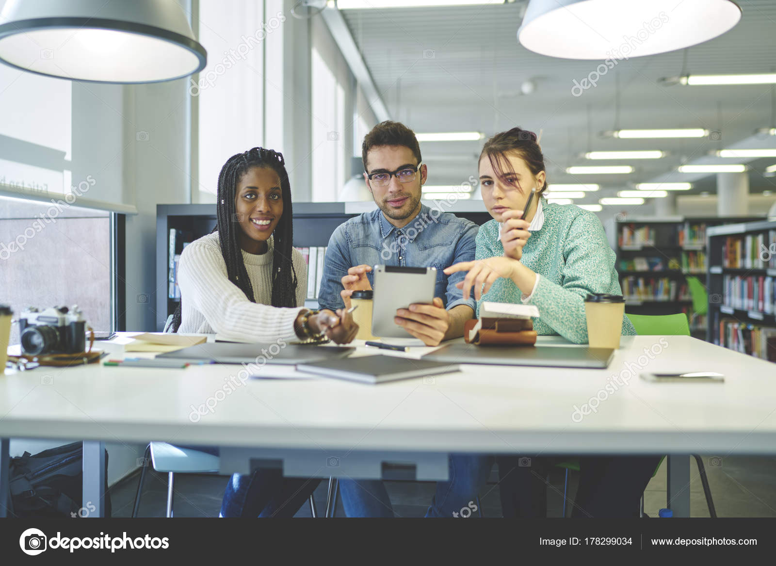 University classmates cooperating preparing for examination in library ...