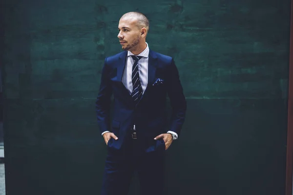 Serious proud CEO dressed in formal wear looking away posing on dark ...