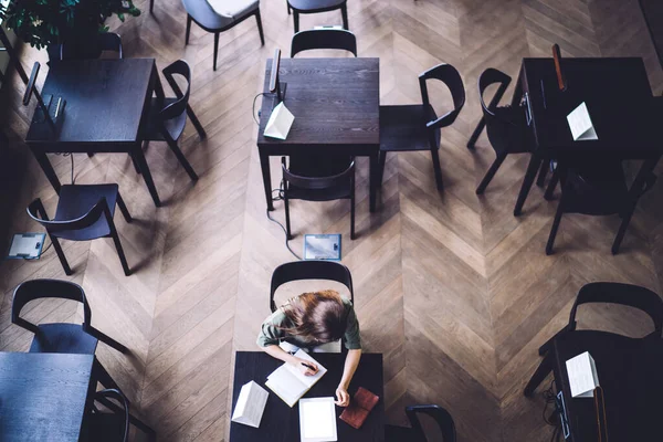 From above woman sitting at table in college library using digital ...