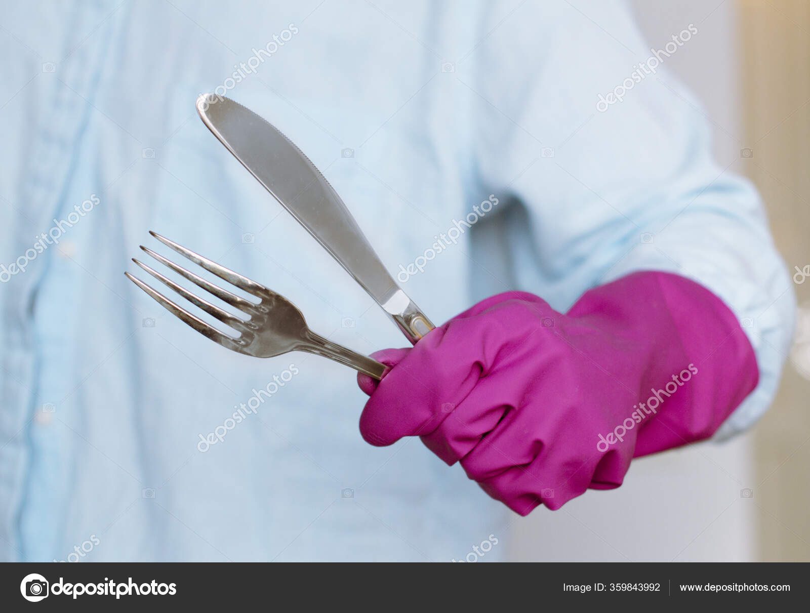 Fork and knife in hand in a household purple glove, disinfection and ...