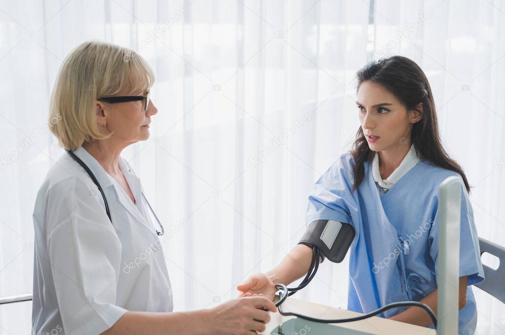 Mujer mayor médico chequeando mujer joven paciente presión arterial. 2023