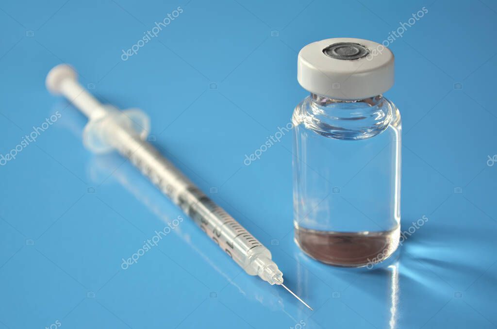 Vial de medicamento y jeringa desechable sobre fondo azul claro ...