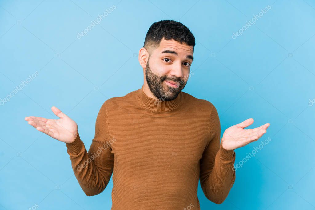 Joven Latino Sobre Un Fondo Azul Aislado Dudando Y Encogiéndose De Hombros En Un Gesto De