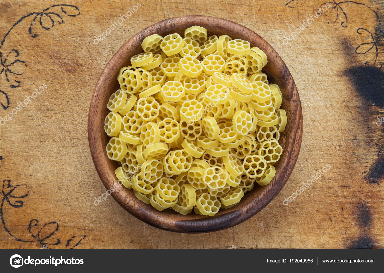 Macaroni ruote pasta in a wooden bowl on a cutting wooden board ...