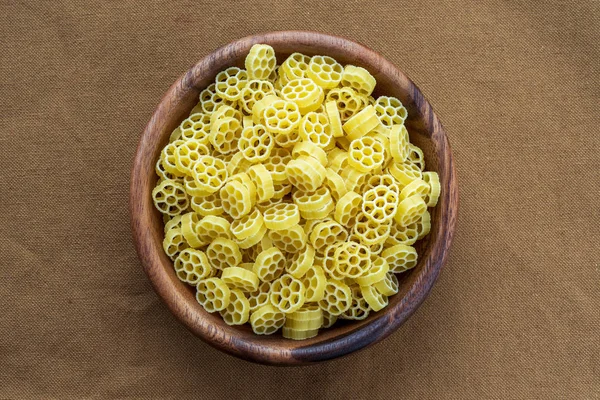 Macaroni ruote pasta in a wooden bowl on a cutting wooden board ...