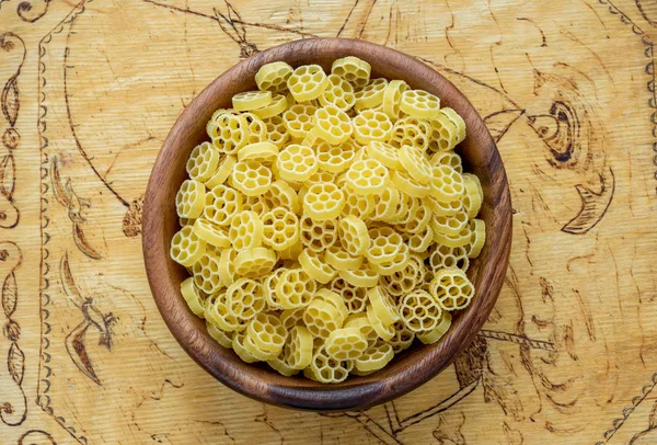 Macaroni ruote pasta in a wooden bowl on a cutting wooden board ...