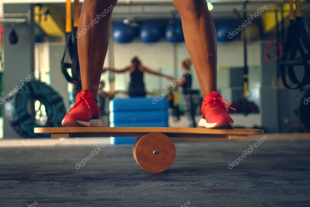 Detalle de las piernas de una persona practicando el equilibrio en un tablero de equilibrio ...