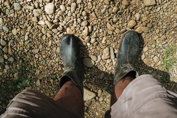 men's feet in muddy rubber boots standing on rocks - Stock Image ...