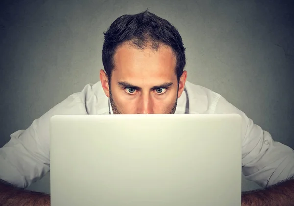 Man hiding behind a laptop staring at screen with a shocked face ...