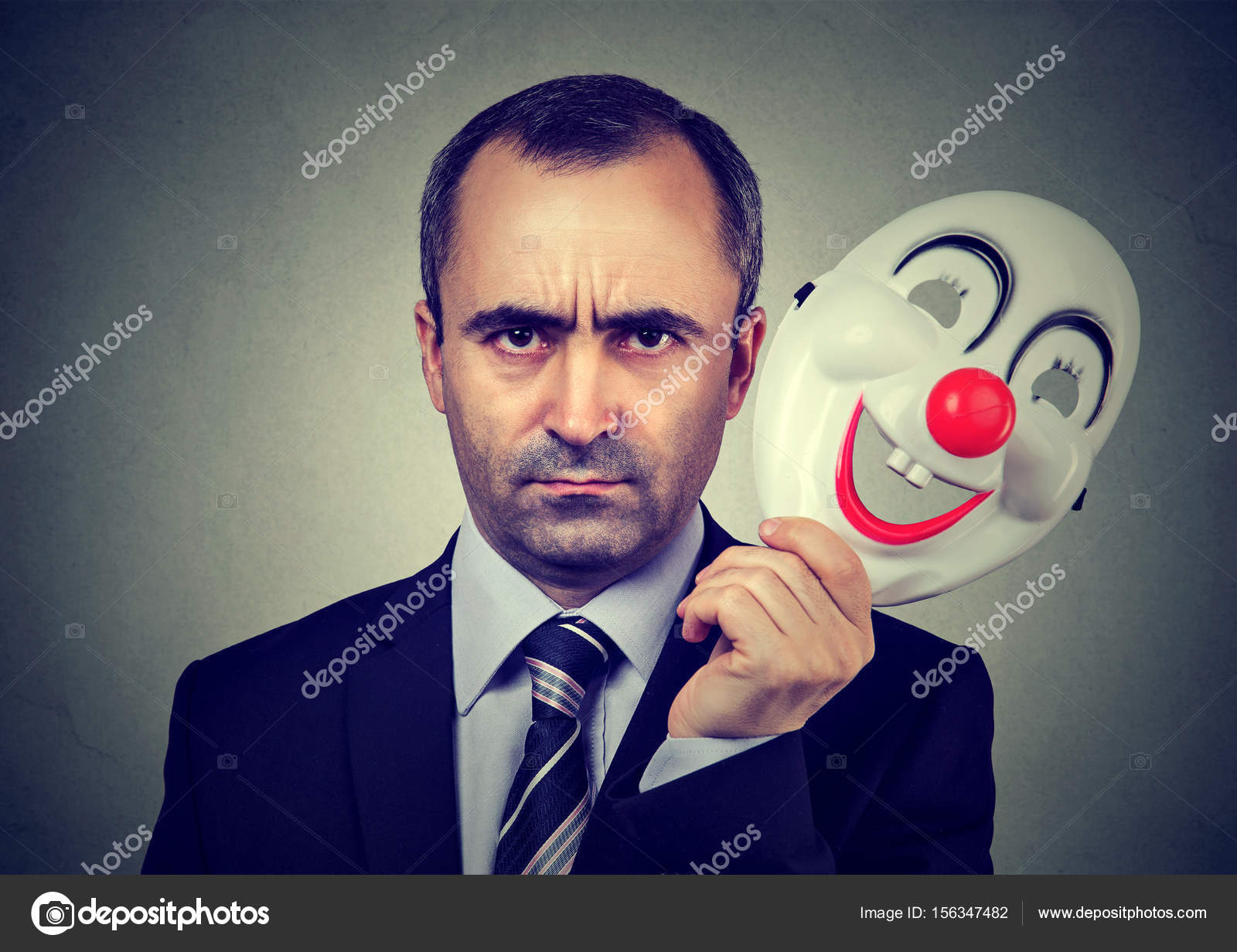 Angry business man taking off happy clown mask — Stock Photo ...