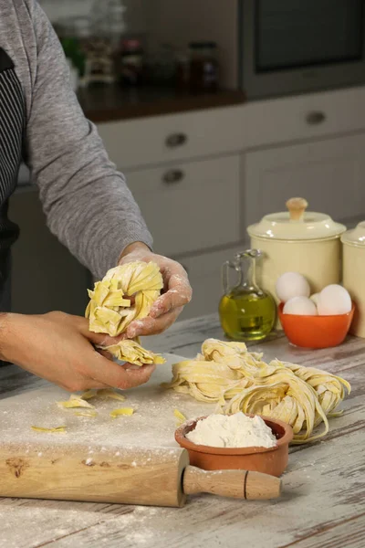 Male hand seen making pasta with dough roller and flour on kitchen ...