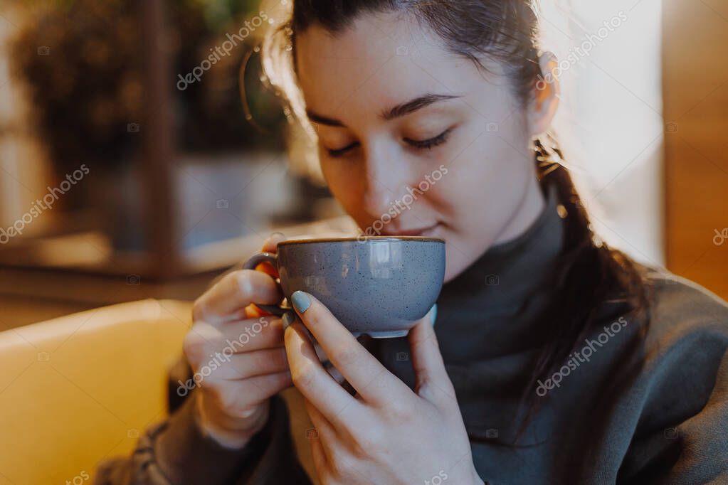 joven chica bonita con una taza grande de café dulce se sienta en una ...