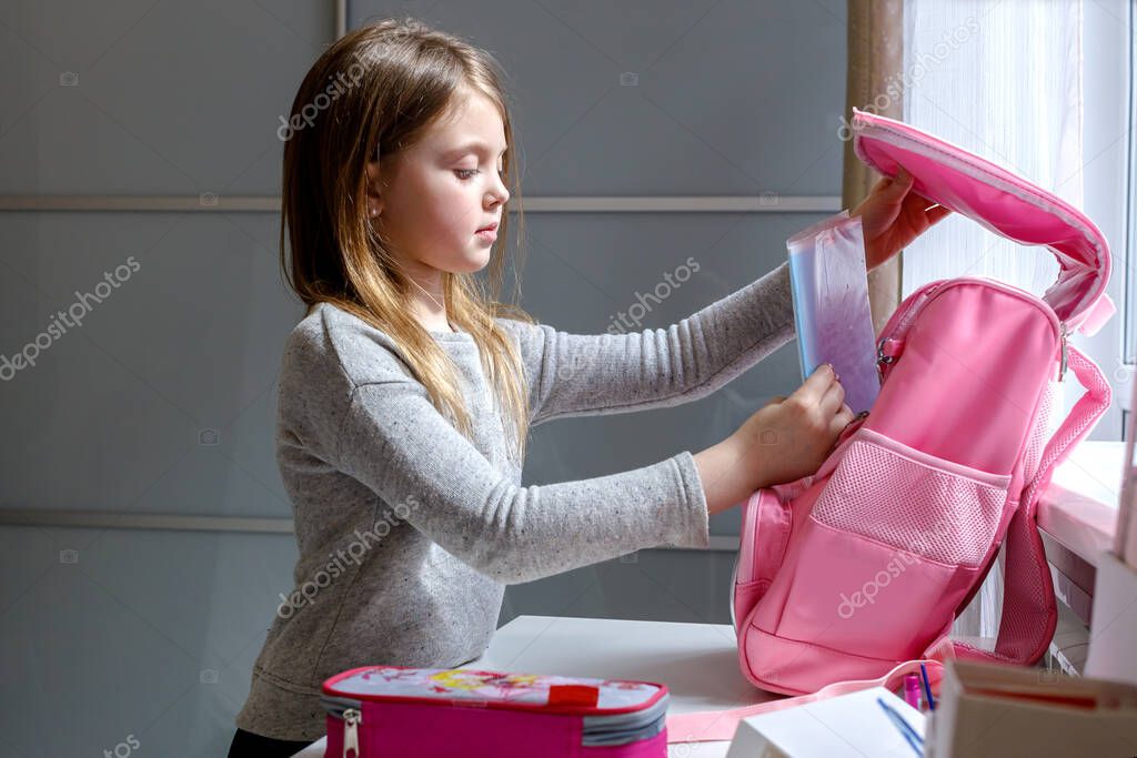 Buena chica preparando para la escuela su mochila. Primer día de ...