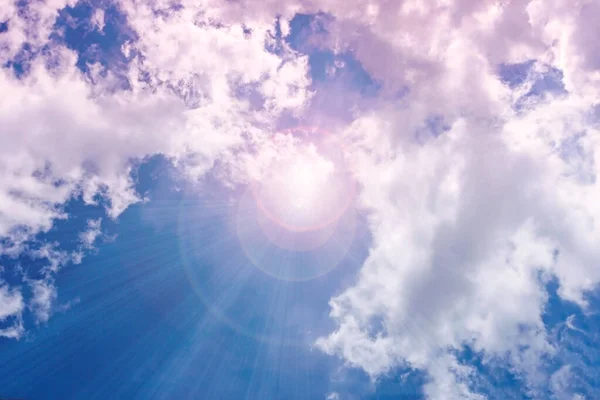 A bright ray of sunshine breaks through the fluffy white clouds. The ...