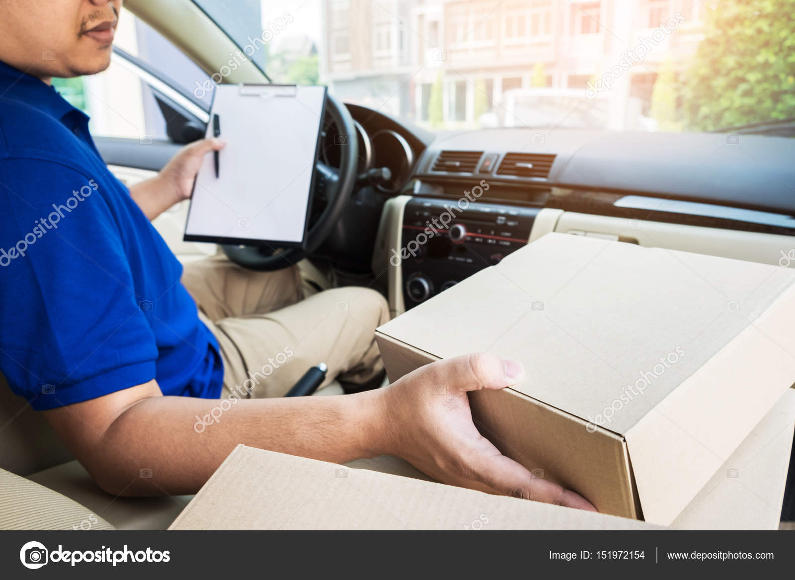 Delivery man with cardboard box checking document list In van an ...