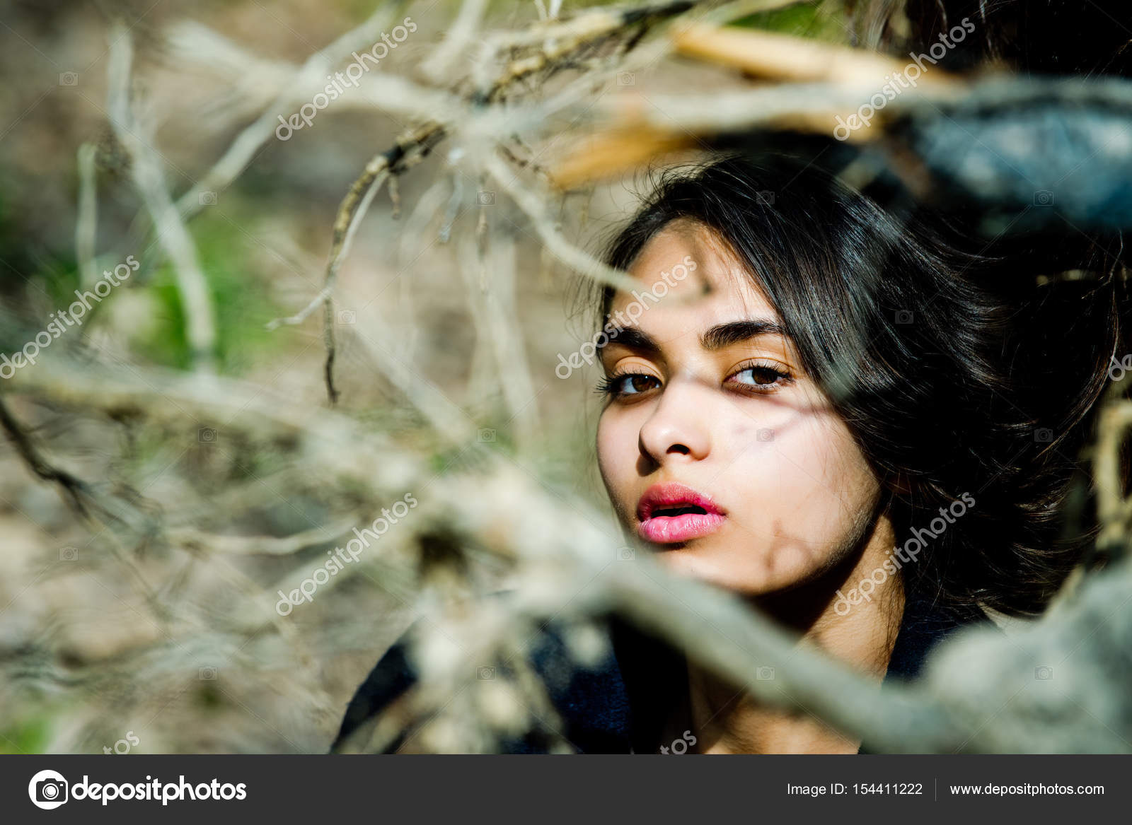 Woman hiding in bare tree branches Stock Photo by ©Tverdohlib.com 154411222