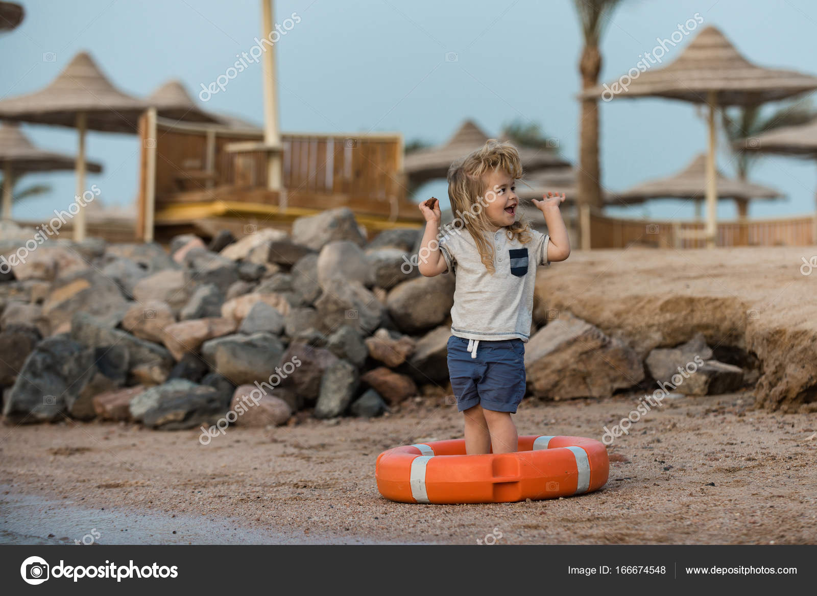 Boy child standing with hands up in life buoy. Stock Photo by ...