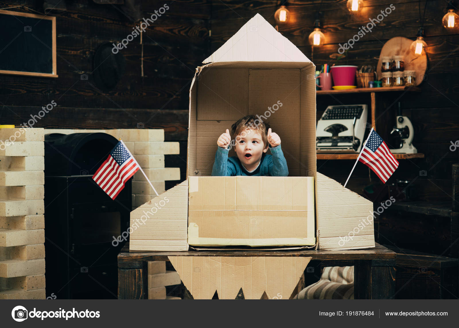 Boy play with rocket, cosmonaut sit in usa rocket made out of cardboard ...