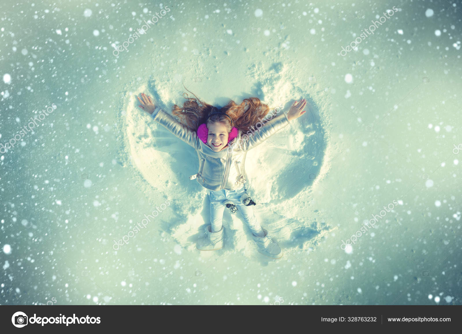 Snow angel made by a kid in the snow. Smiling child lying on snow with ...