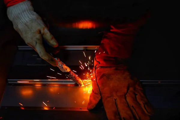 A woman wearing a pink long sleeve jacket, welding mask and leather ...