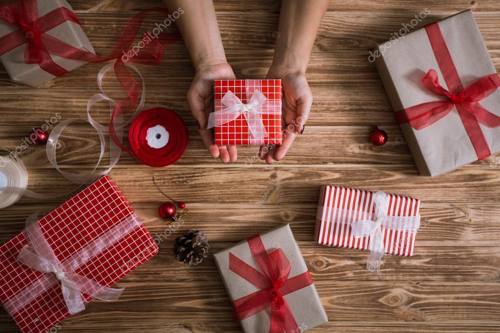 Female hands wrapping xmas gifts into paper and tying them up with red ...