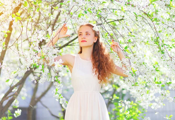 Beautiful young woman enjoying spring flowers over garden backgr ...