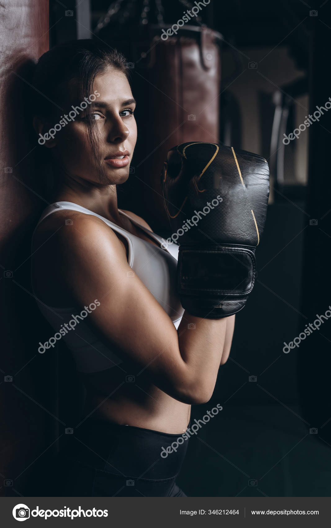 Boxeadora posando con saco de boxeo, sobre fondo oscuro. Concepto de ...